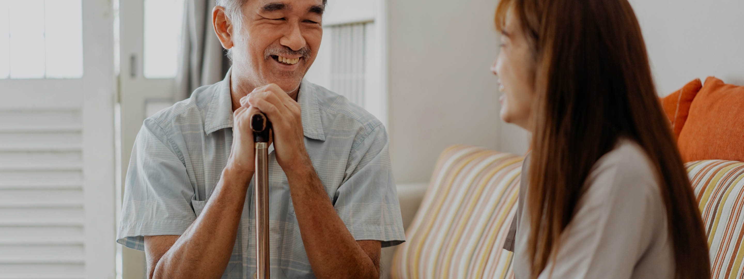 A laughing client sits on a couch next to a support worker